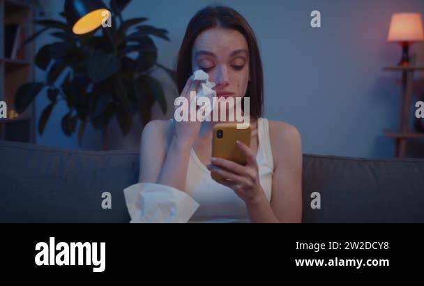 Close up of young woman wiping tears from her face with paper tissue ...