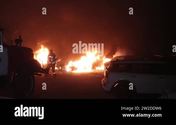 Fire of a car on city street man trying to put out a fire with ...