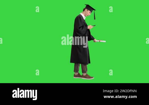 Graduation: Happy student walking and texting on his phone on a Green ...