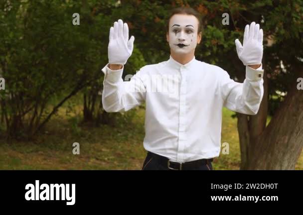 Young funny mime behind an invisible glass box or wall. Mime on the ...