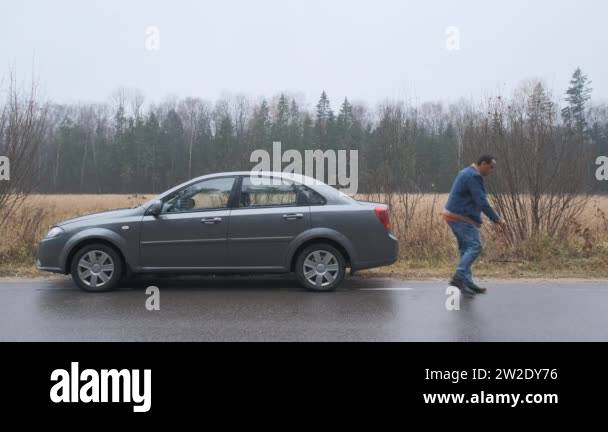 A male driver places an emergency stop sign on the road. Car with ...