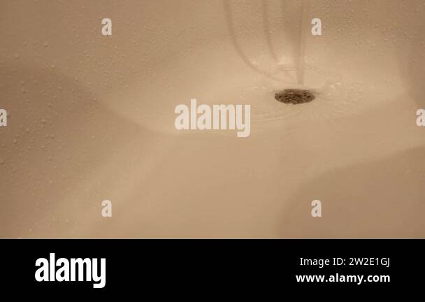 Water flows from the tap into the bathtub and flows down the drain ...