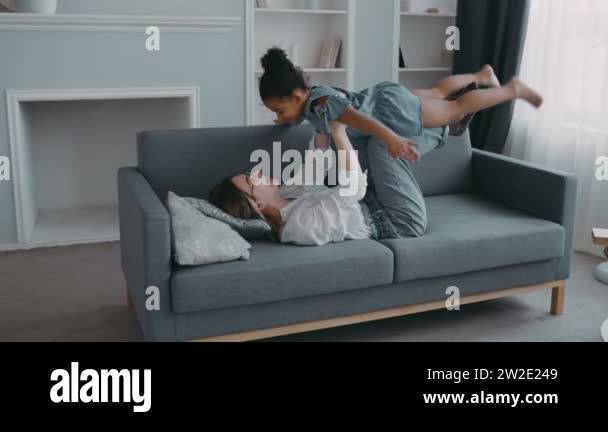 Friendly beautiful family healthy young mother lifting cool child daughter up playing plane on ...