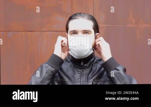 man puts on and removes a disposable mask to protect against the ...