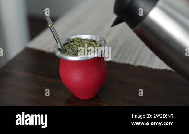Man making yerba mate tea. Close up pouring hot water into traditional ...