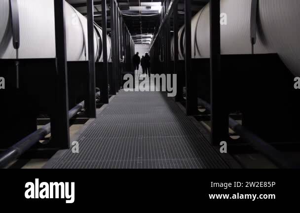 Rear view of three men walking along water treatment tanks at the power ...