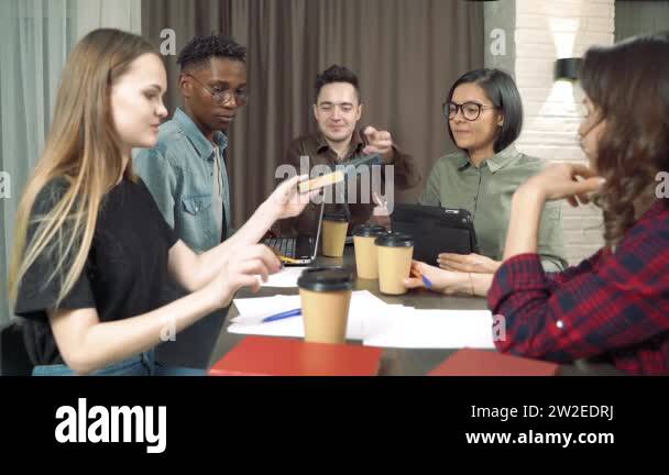 Group of multi-ethnic young people working together laughing at a funny ...