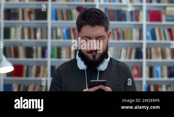 Young Cucasian male library worker or with headphone tapping and ...