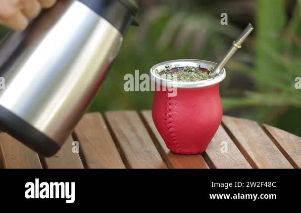 Man making yerba mate tea. Close up pouring hot water into traditional ...
