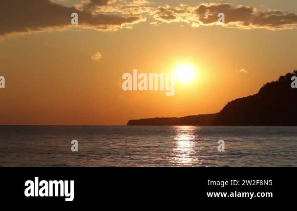 Red sunsets over sea . The sun touches horizon. Red sky, yellow sun and ...