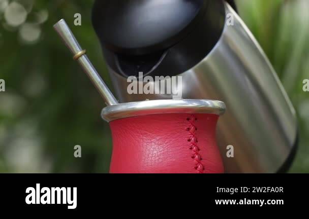 Man making yerba mate tea. Close up pouring hot water into traditional ...