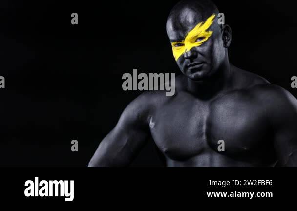 Man bodybuilder athlete with yellow color on face art and black body ...
