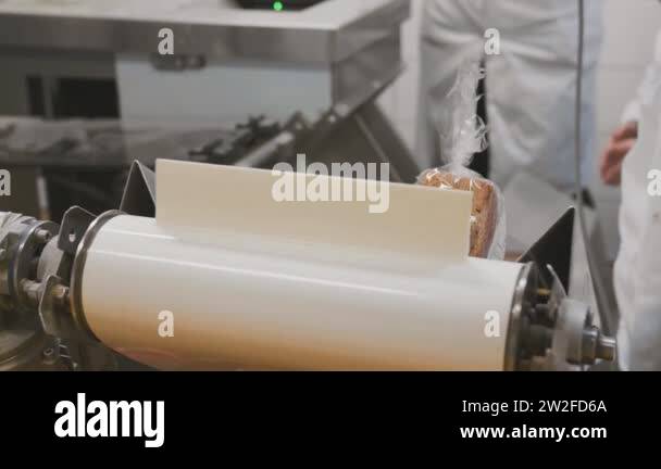 Packing conveyor. Packed long loaves of bread are moving on the ...