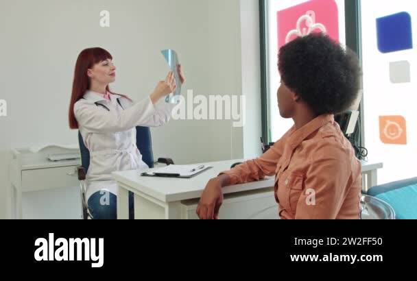 Young female doctor checking x-ray of lungs, advising patient with ...