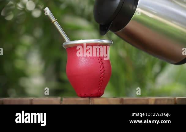 Man making yerba mate tea. Close up pouring hot water into traditional ...