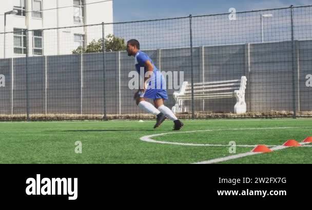 Side view of a mixed race male football player wearing a team strip ...