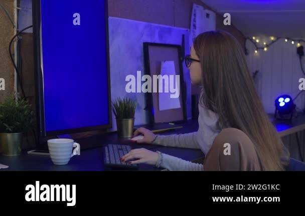 The girl works at home at the computer with a blue, green screen. The ...