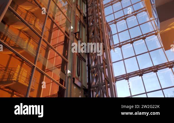 Modern elevator moves down and up at corporate building in sunset ...