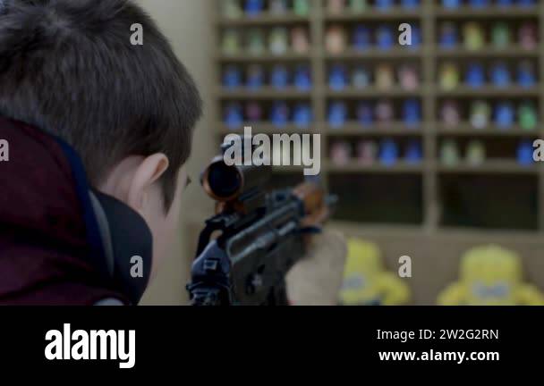 The boy in the shooting range aims at the can, shoots with a rifle and ...