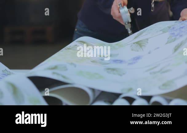 Quality control of wallpaper in a factory, checking the thickness of ...
