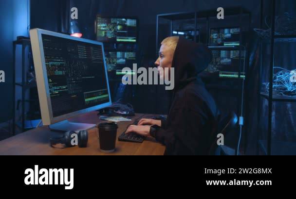 Side view on Caucasian female hacker in hood working on computer and ...