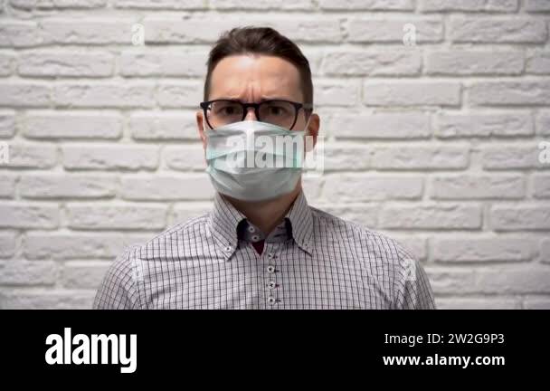 Young brunet man in gray checkered shirt in protective medical mask ...