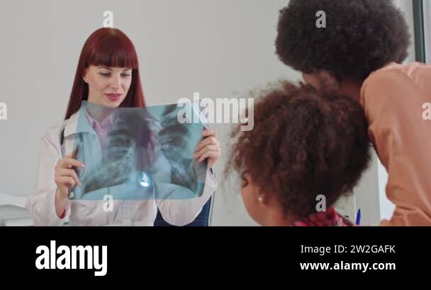 Female pediatrician holding a lung x-ray in her hands. The doctor ...