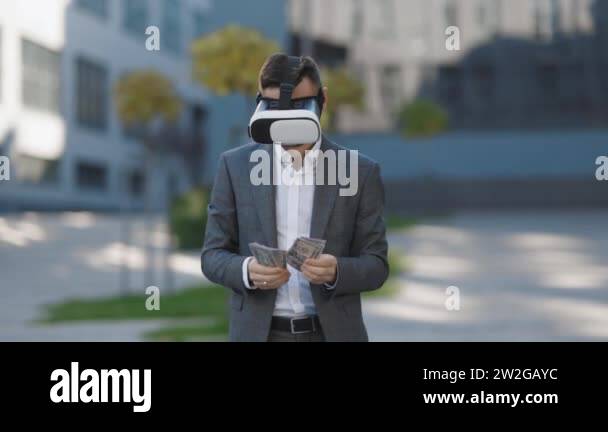 Rich man wearing virtual reality headset counting money. Young ...