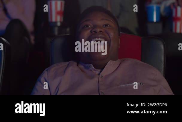 Close up of happy young man face watching comedy film in cinema ...