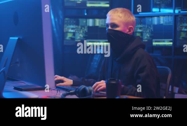 Caucasian woman hacker with blond short hair and masked face sitting in ...