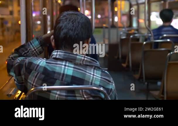 Sad Chinese man from behind on a bus scratching his head at night in ...