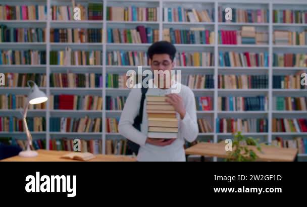 Young happy handsome Latino guy in glasses with stack of textbooks ...