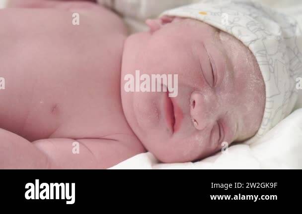 A close-up portrait of a crying newborn in a primordial grease that ...