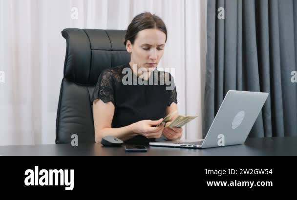 Lady boss counting dollar bills. Woman counts cash money in the office. Young smiling female in ...