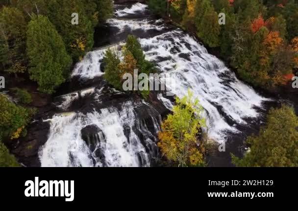 Beautiful travel aerial lowering down over Bond Falls waterfall on the ...