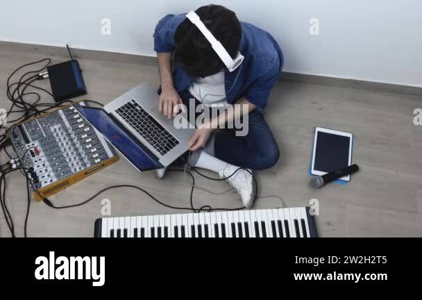 Young man in sound recording studio. Up view of guy sitting on floor ...