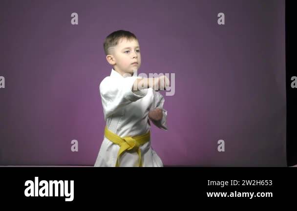 Little athlete is training punches arms in karate stance on purple ...