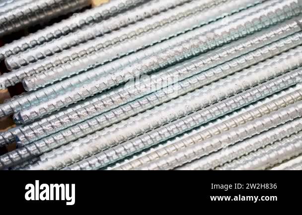 Many shiny bars of steel rebar, different in diameter and length lay on ...