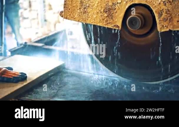 Automated circular saw cuts the stone slab at industrial factory. Process of cutting stove with ...