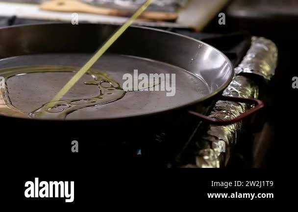 Into big shallow pan chef pouring oil during heating pan on gas oven ...