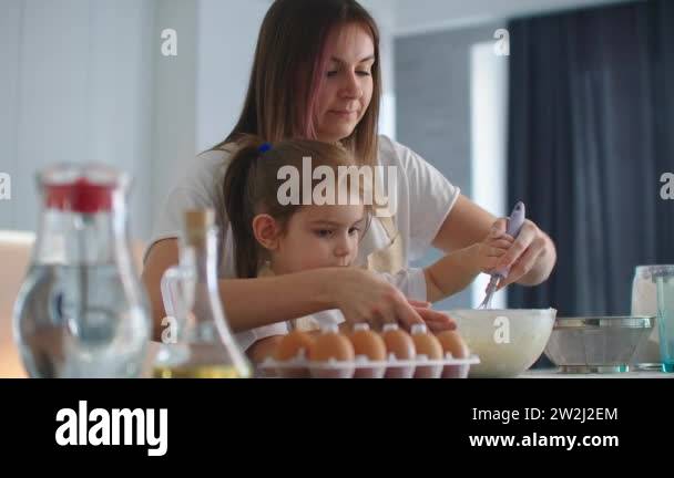 A smiling mother helps her daughter learn how to make a pie. Teach a ...