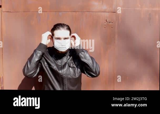 man puts on and removes a disposable mask to protect against the ...