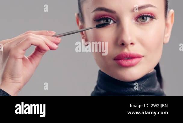 Woman makes makeup. Young woman paints her eyelashes with an eyelash ...
