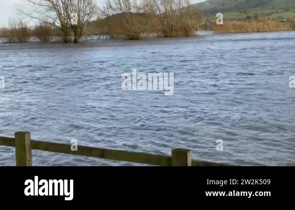 Wooden fence submerged in by muddy flood water after extreme weather ...