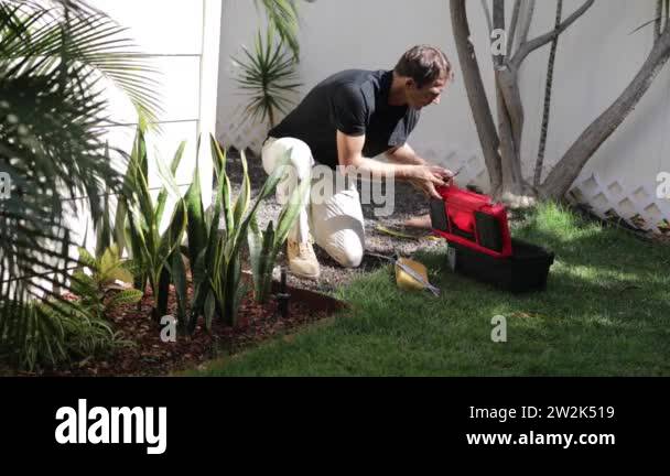 Plumber Man fixing Sprinkler Head in backyard. Grass Field Sprinklers ...