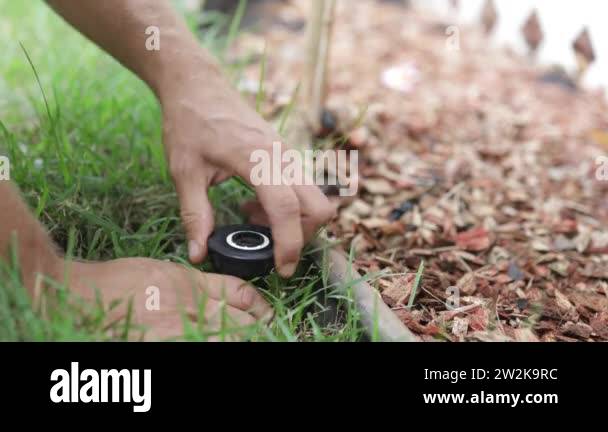 Plumber Man fixing Sprinkler Head in backyard. Grass Field Sprinklers ...