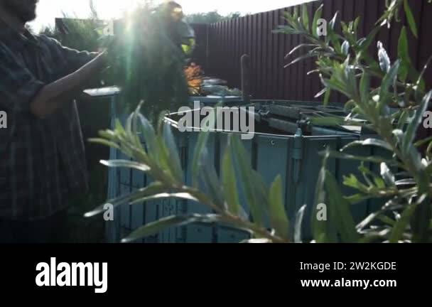 Person throws garden waste into compost heap to make organic fertilizer ...