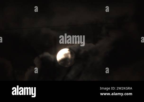 Full moon appearing and disappearing on dark and cloudy night sky Stock ...