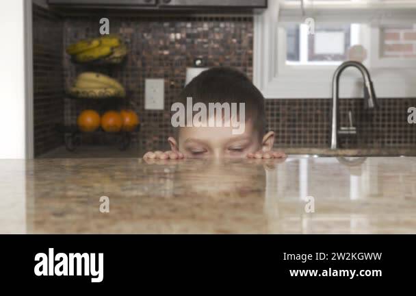 little boy hiding in the kitchen under the counter top table and ...