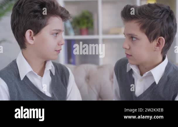 Close-up side view of two identical twin brothers looking at each other ...